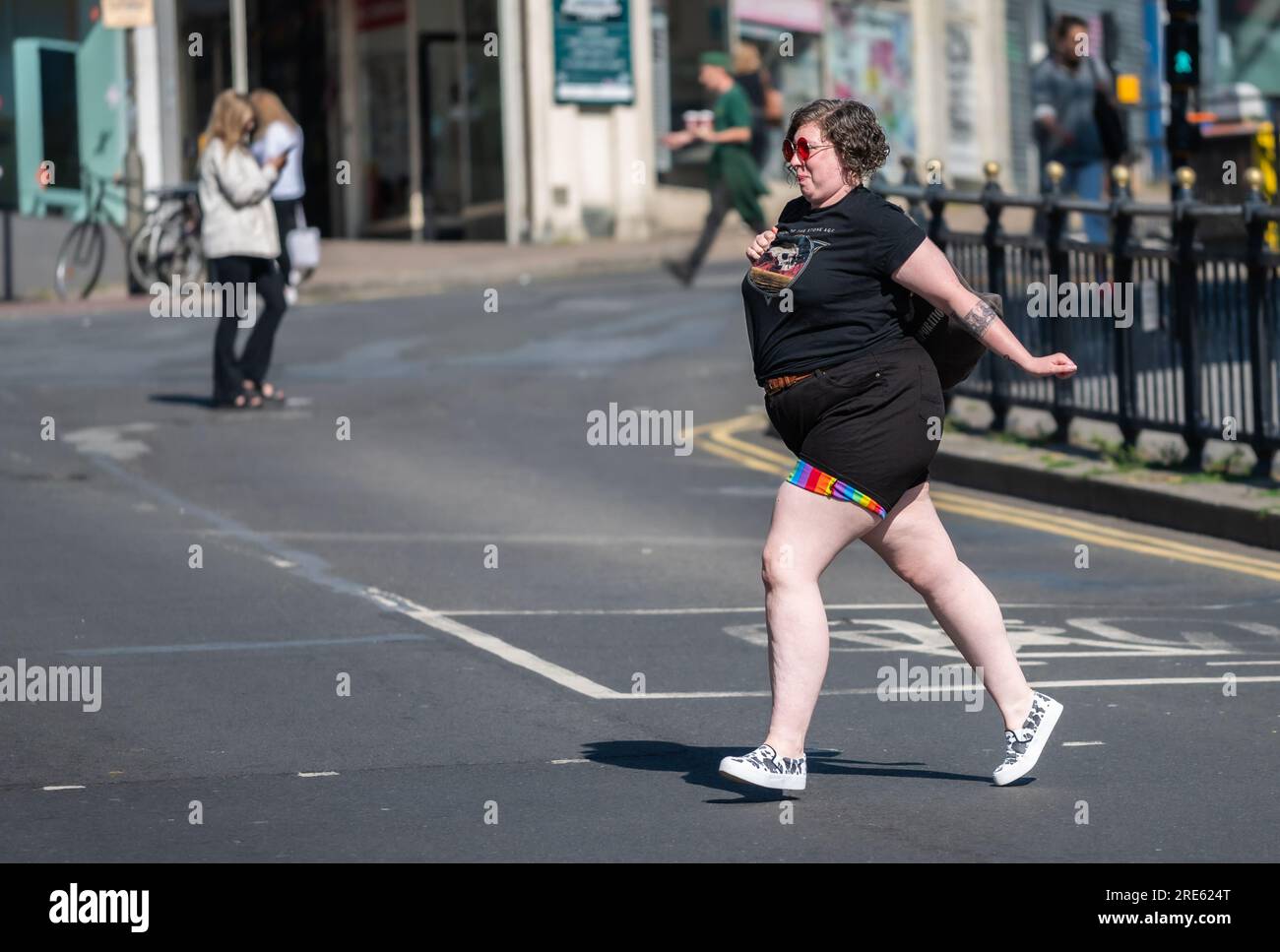 Overweight young lady crossing a busy road in England, UK, looking ...