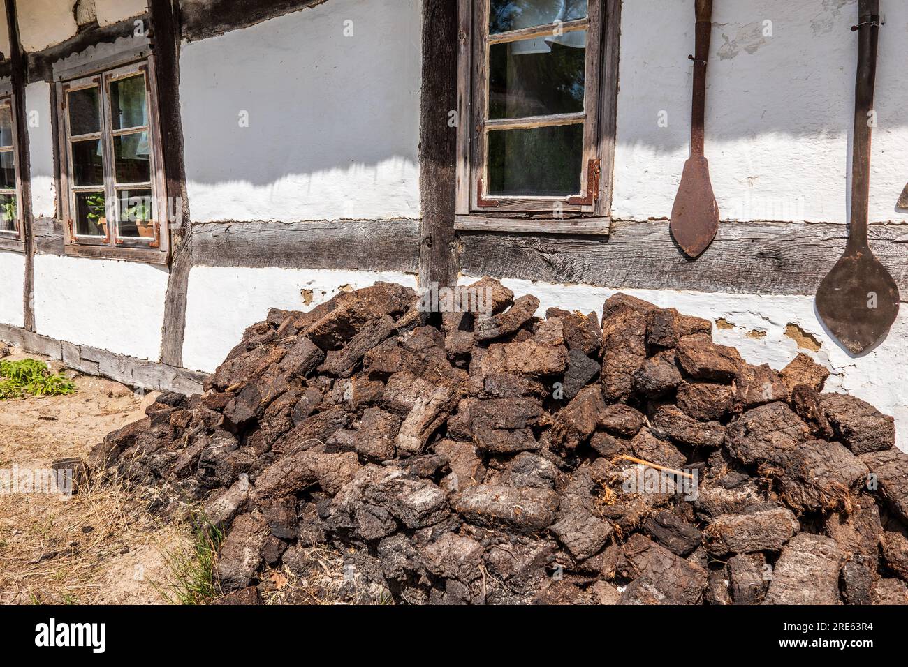 Stack of dried peat for fuel outside an old wooden farmhouse in Kluki ...