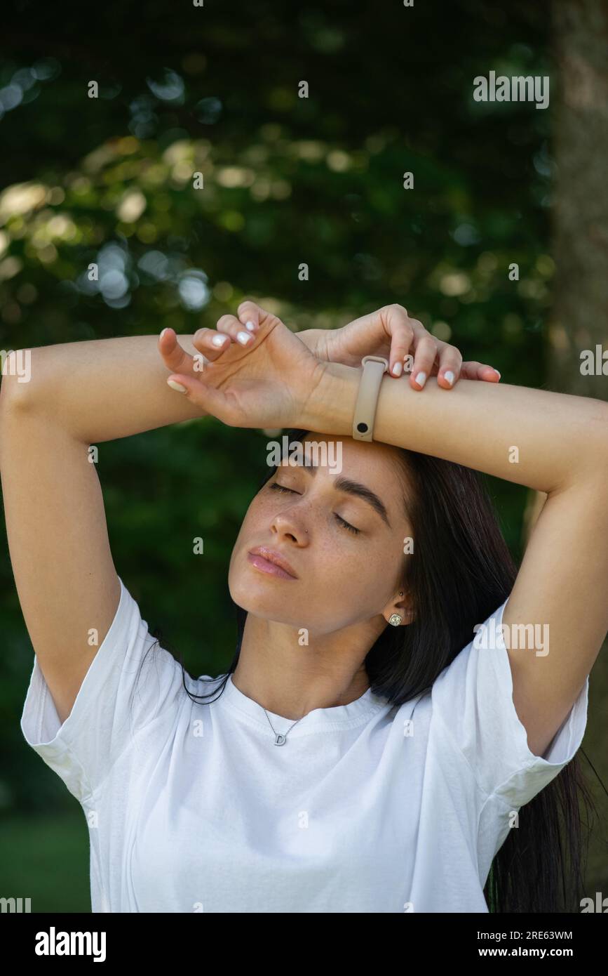 A young woman stands with her eyes closed in the park. Fresh air, walk ...