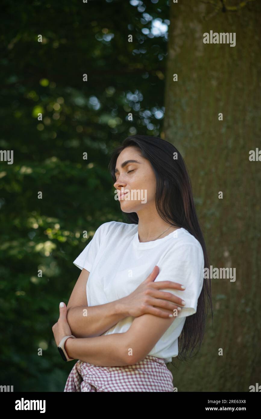 A young woman stands with her eyes closed in the park. Fresh air, walk ...