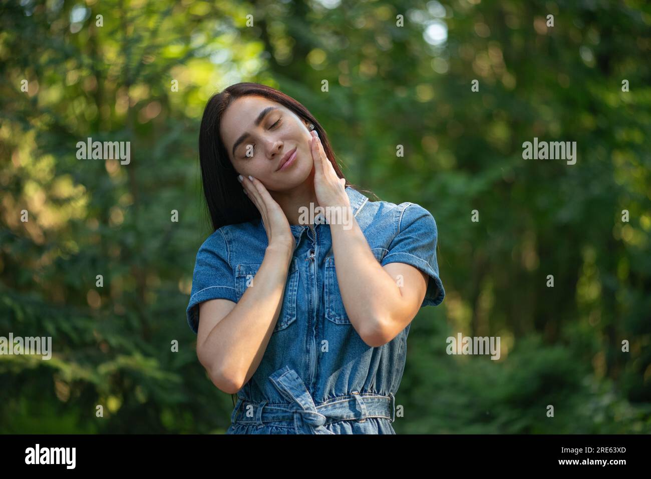 A young woman stands with her eyes closed in the park. Fresh air, walk ...