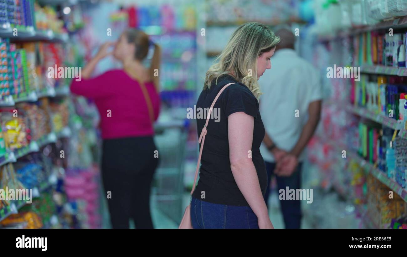 Grocery customers looking for products at aisle shelf searching for ...