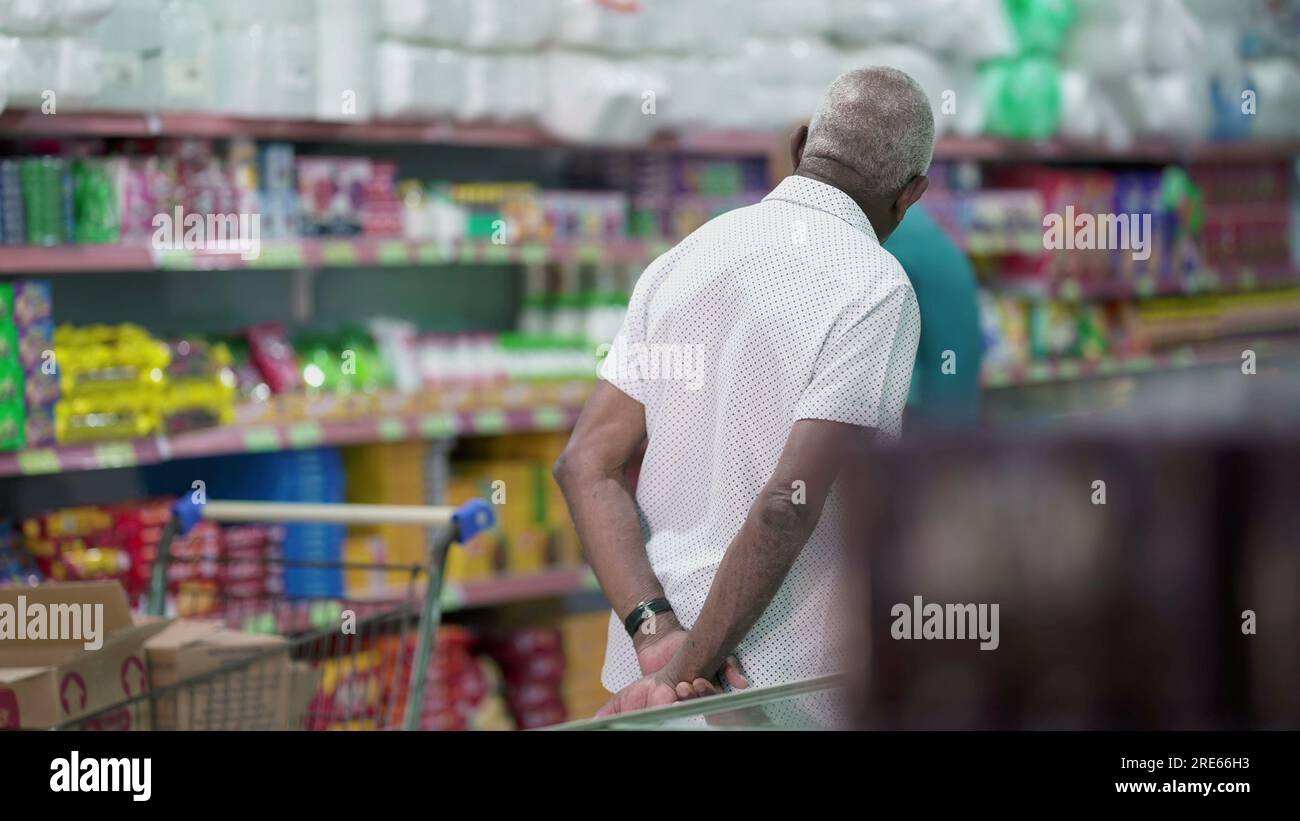 Back of a senior customer browsing at products at grocery store ...
