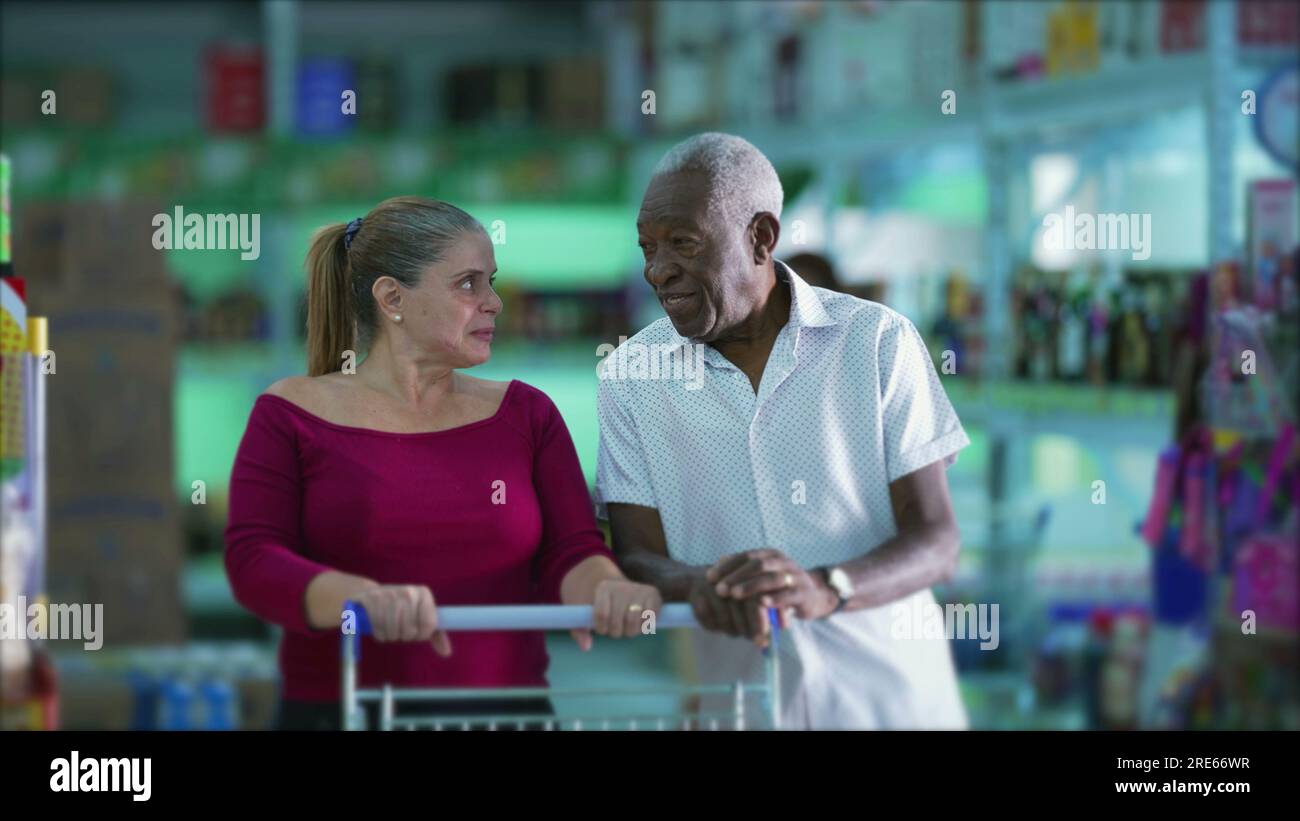 Diverse customers conversing inside grocery store with shopping cart ...