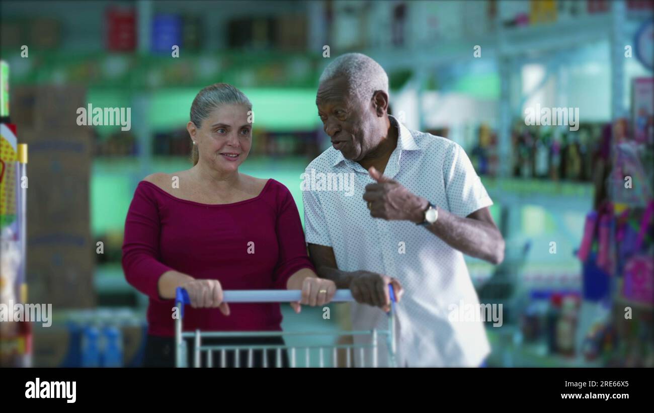 Diverse customers conversing inside grocery store with shopping cart ...
