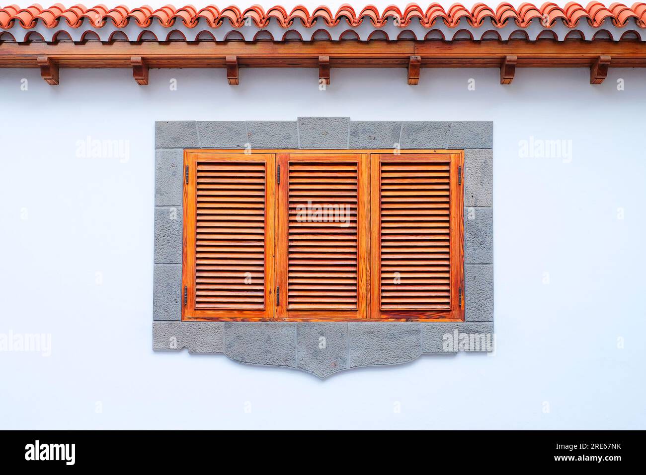 Window shutters in an old classic villa with a white wall and red tiled ...