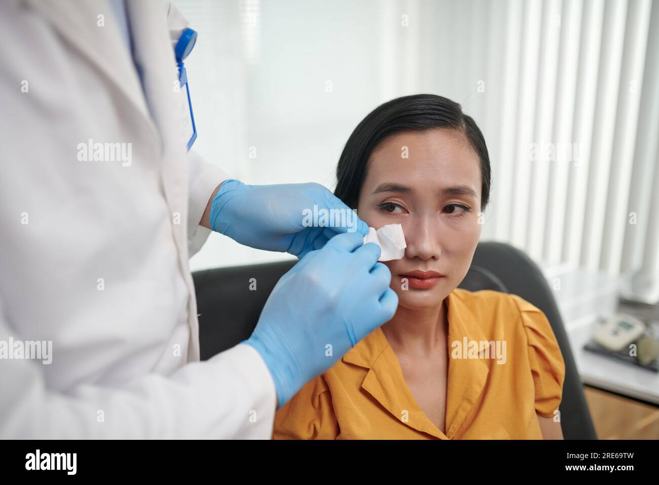 Plastic surgeon taking off patch to check nose of patient after ...