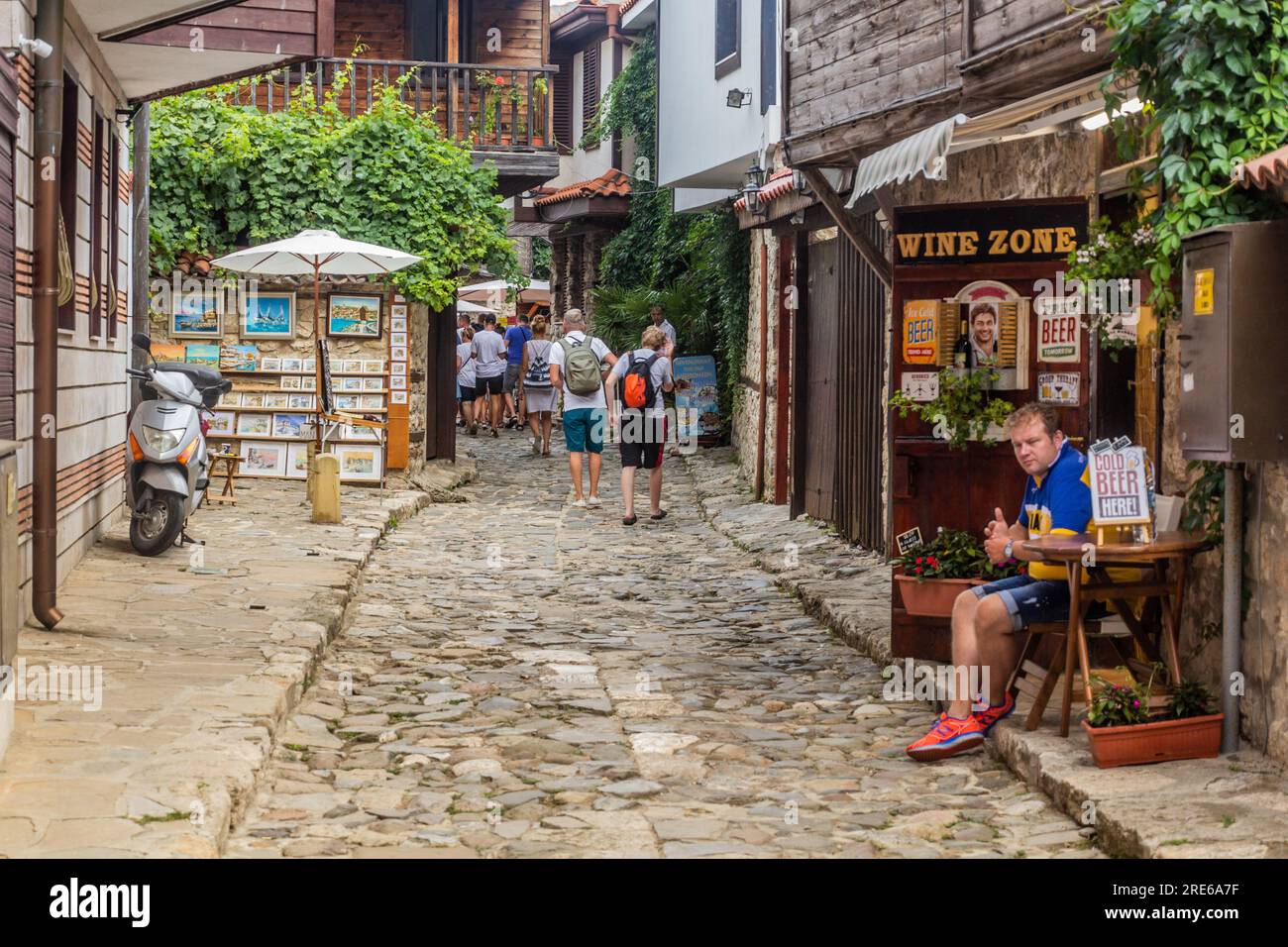 NESEBAR, BULGARIA - JULY 24, 2019: Tourists walking on a narrow street ...