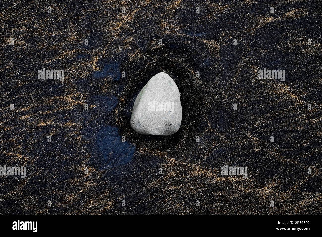 A single centered isolated stone on a backdrop of basalt beach sand ...
