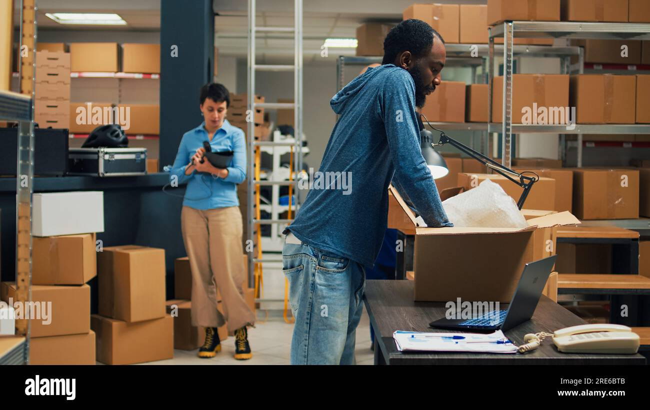 Business owner arranging merchandise in cardboard packages, putting ...