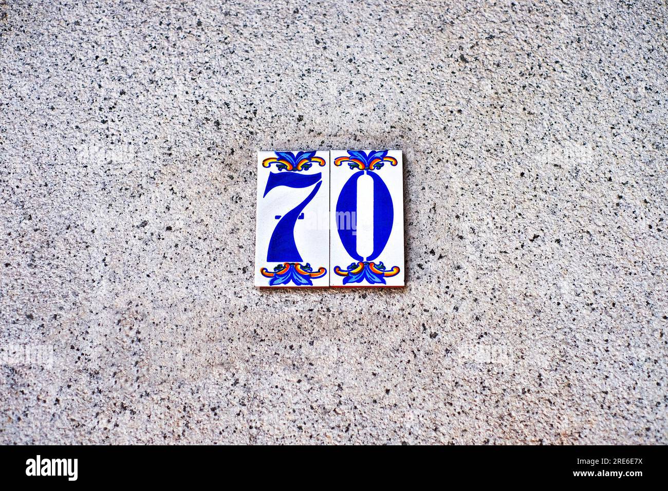 Number 70, seventy, blue digits on floral tiles, on light spotty ...