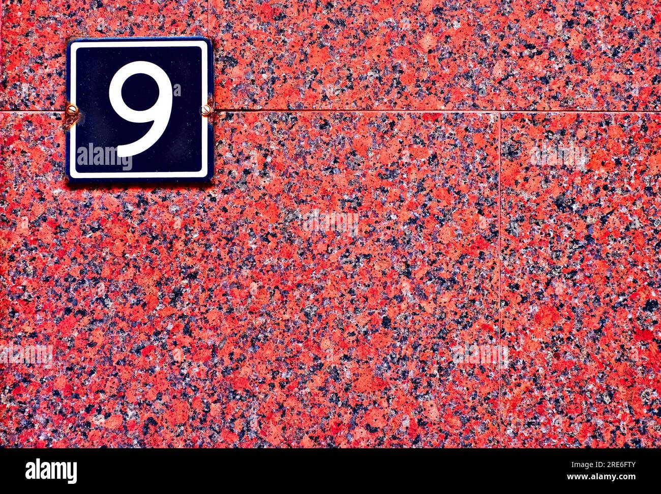 Number 9, nine, white digit on a dark plate on a granite background ...