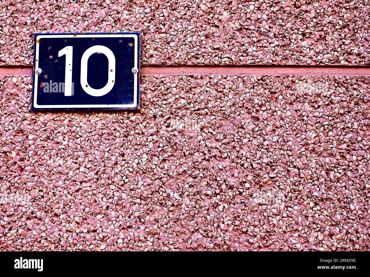 Number 10, ten, white digits on a dark plate, on pink rough background ...