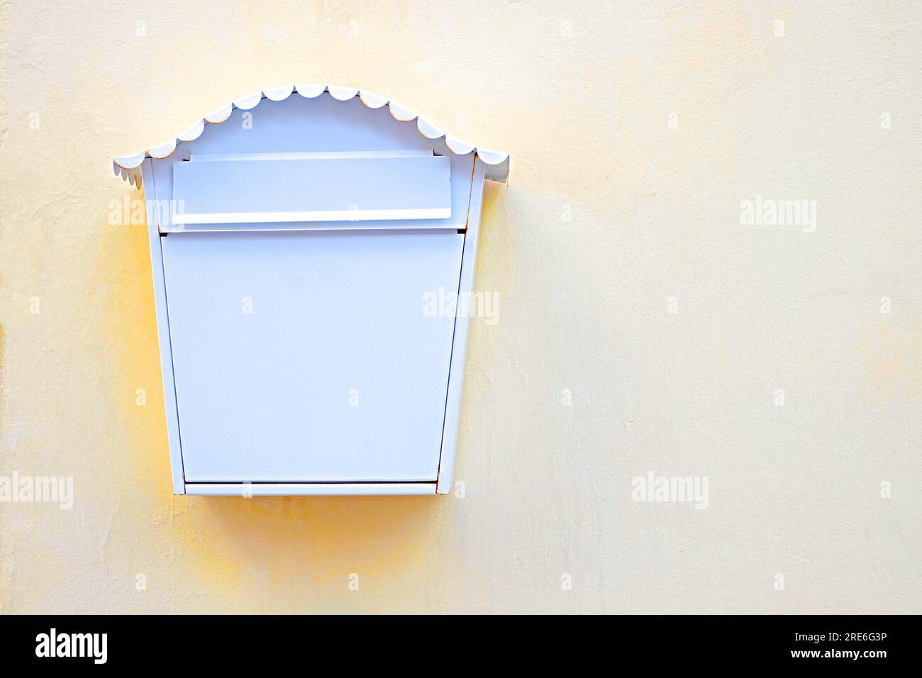 Single elegant white mail box on light pastel yellow wall, offset with ...