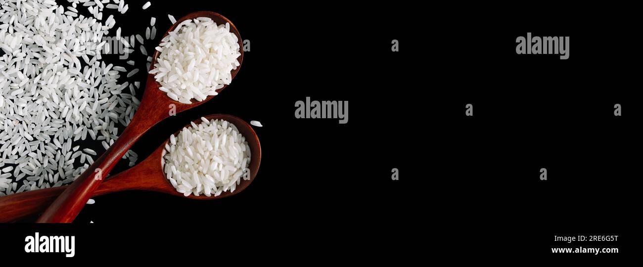 White rice in wooden spoons on black background. Raw grains of long ...