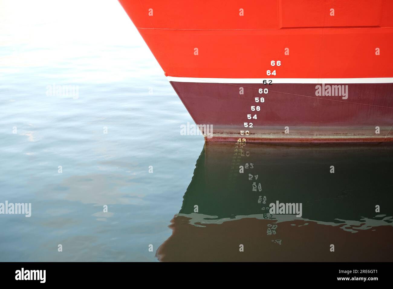 The bow of a red ship with a white waterline and draft (depth) marks ...