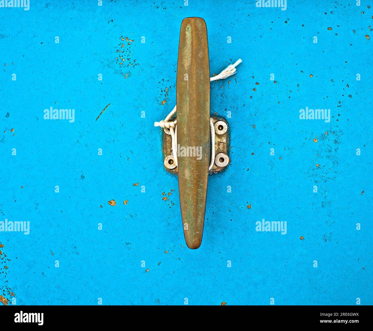 A bronze cleat and a piece of a white string on blue background ...