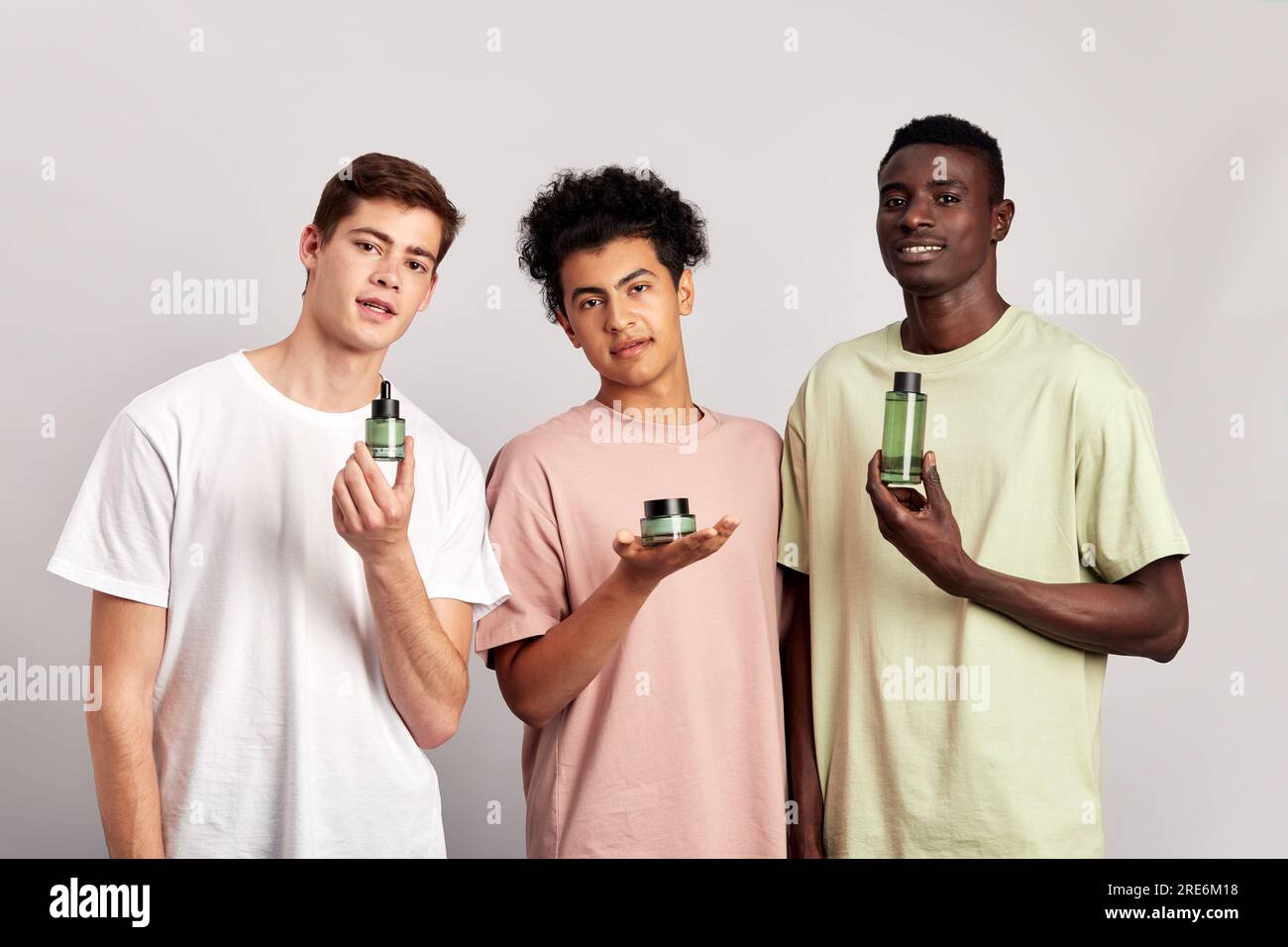 Three young handsome men of different races with cosmetic products in ...