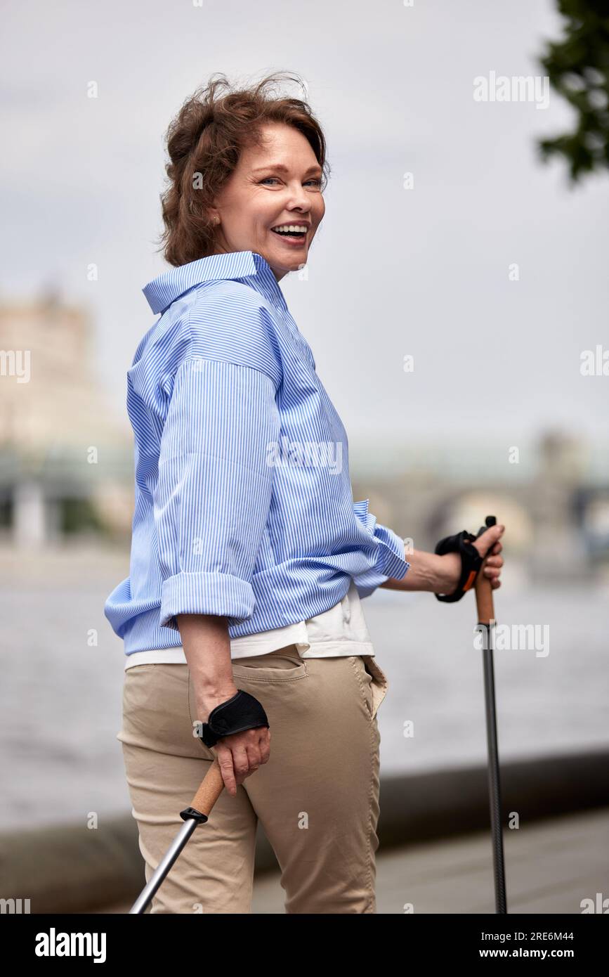 Attractive mature woman with nordic walking poles. Senior lady walking ...