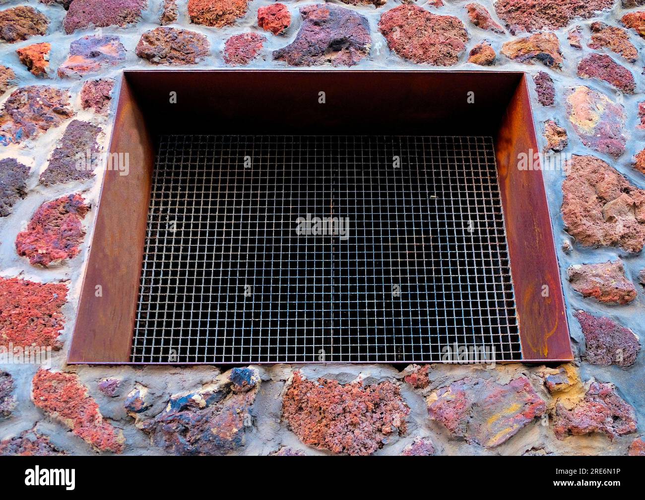 Big rusty air vent hole in a stone wall, protected with rusting iron ...