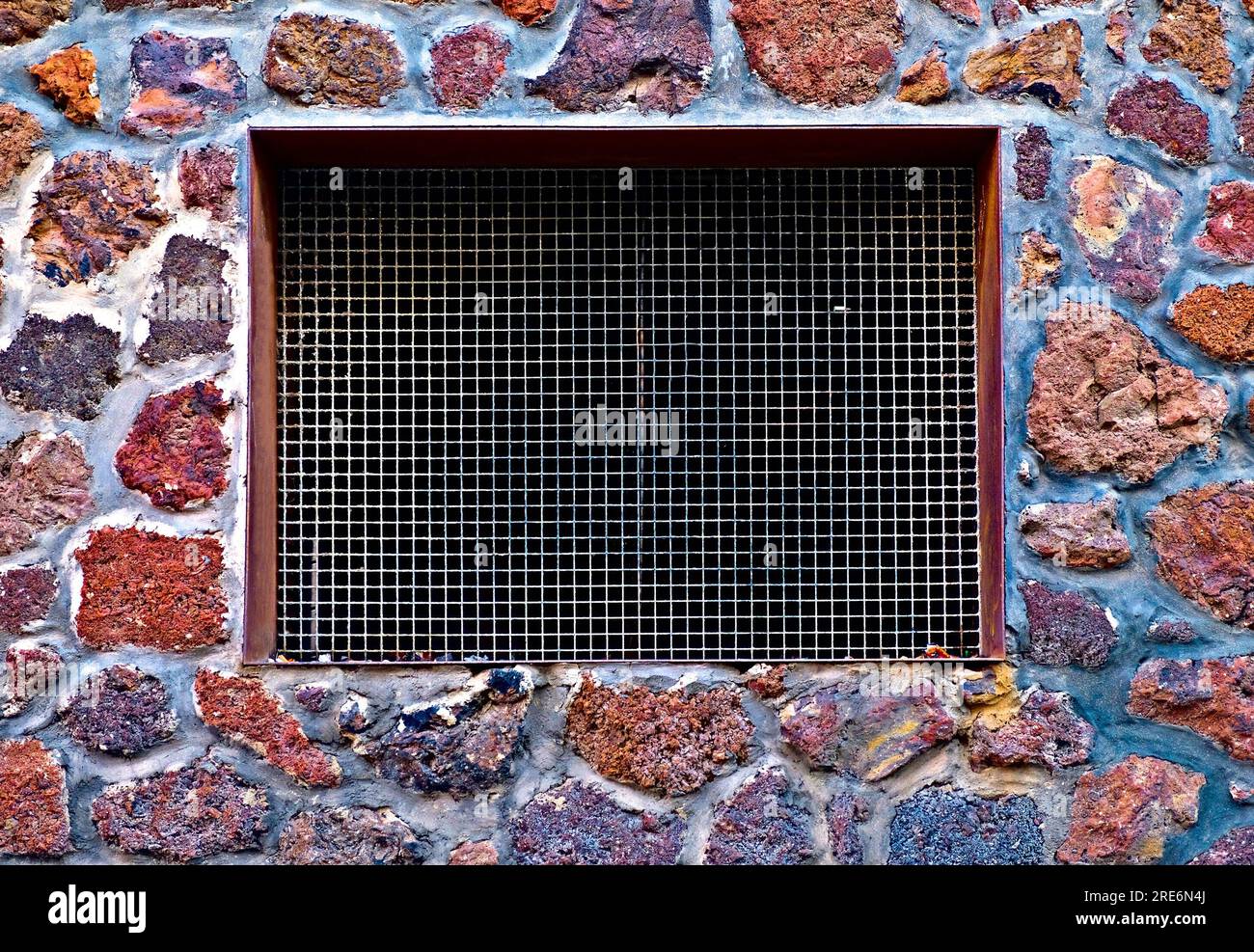 Big rusty air vent hole in a stone wall, protected with rusting iron ...