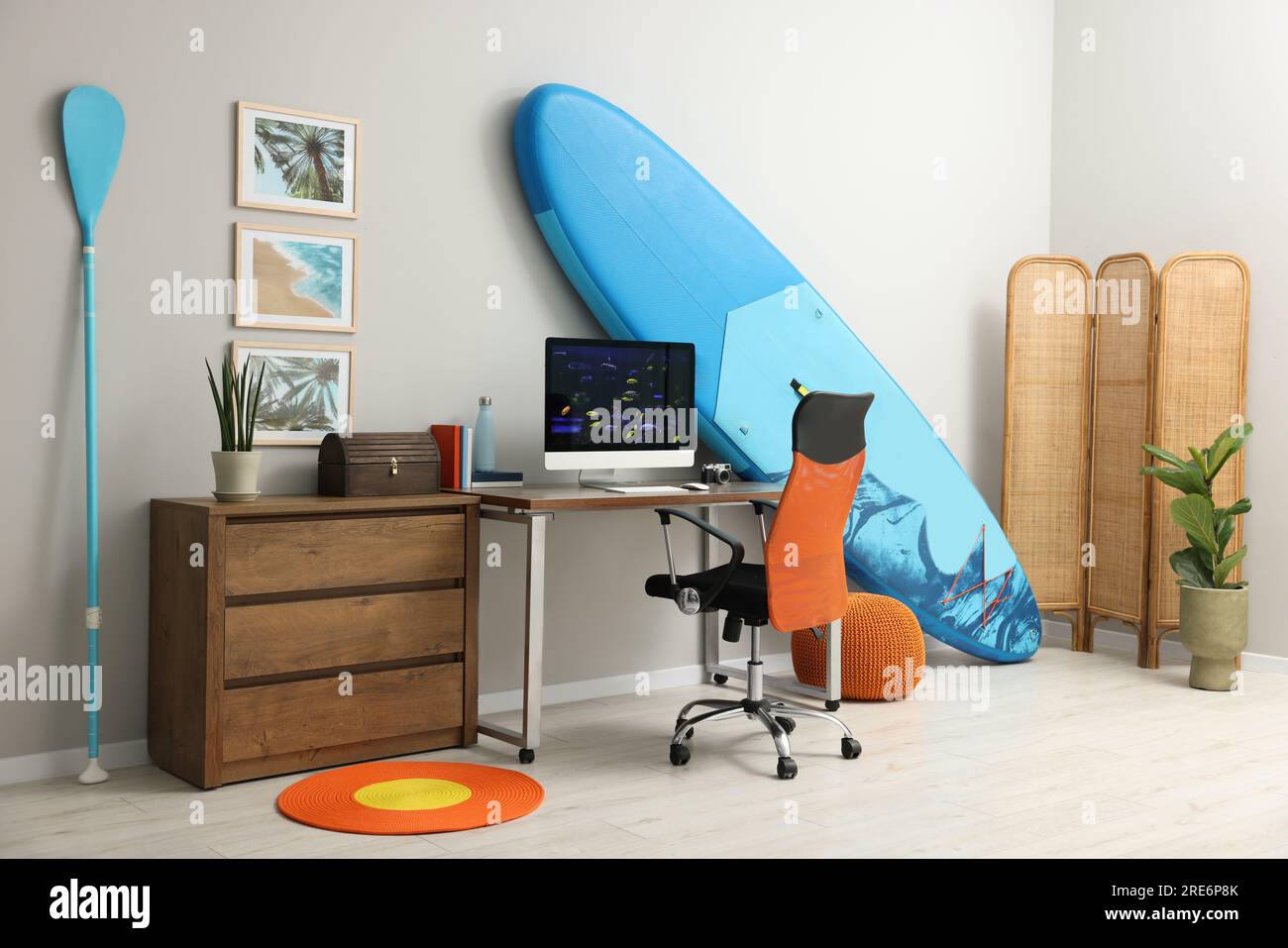 Stylish workplace with modern computer and SUP board near light wall in ...