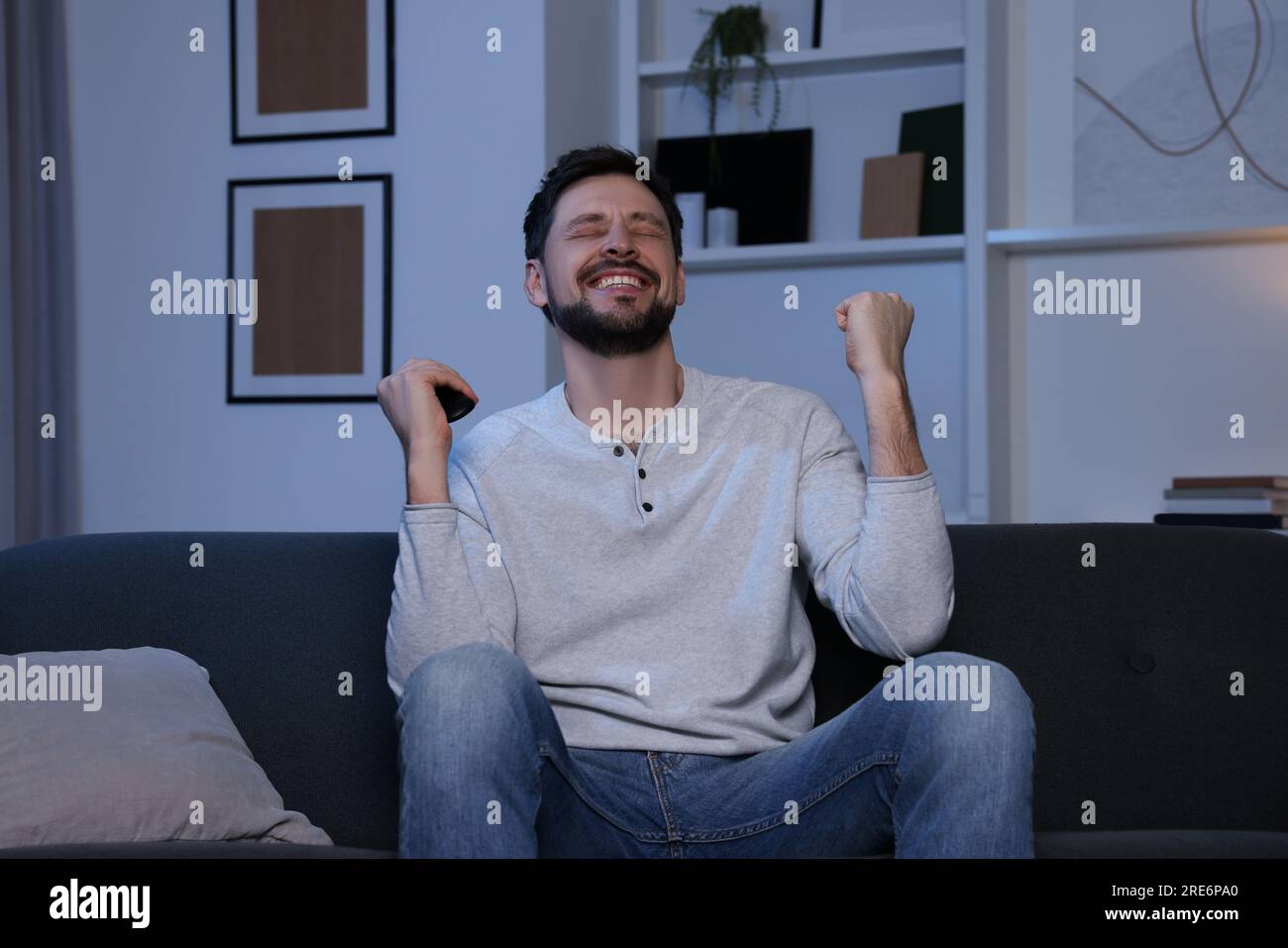 Emotional man with remote controller watching tv at home Stock Photo ...