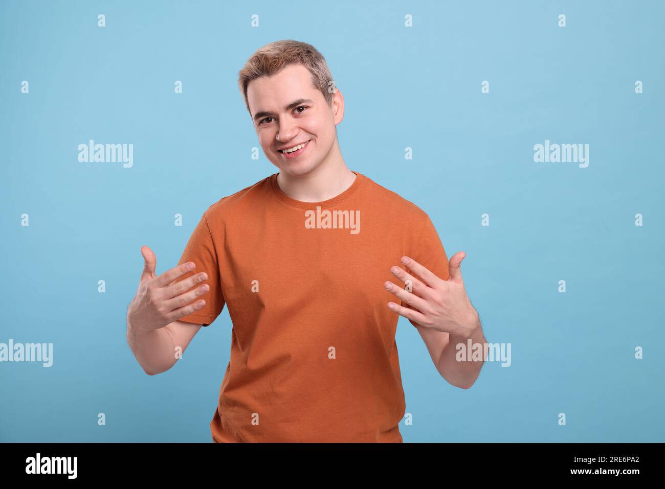 Happy man inviting to come in against light blue background Stock Photo ...