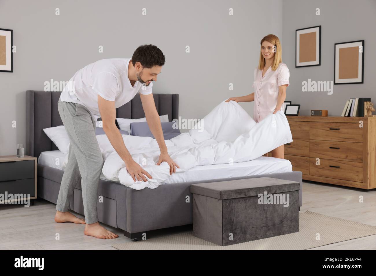 Couple changing bed linens in room. Domestic chores Stock Photo - Alamy
