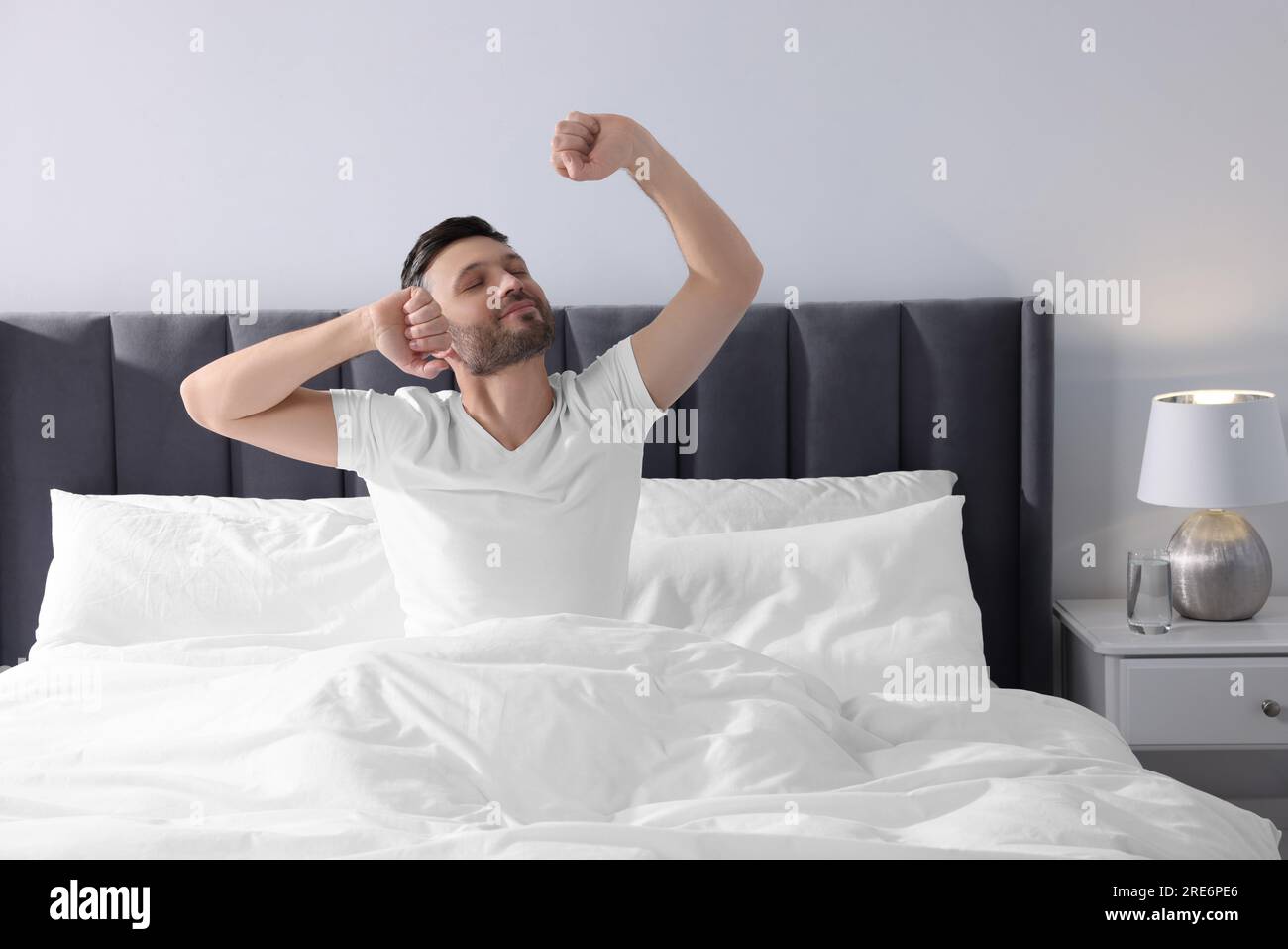 Handsome man stretching in soft bed at home in morning Stock Photo - Alamy