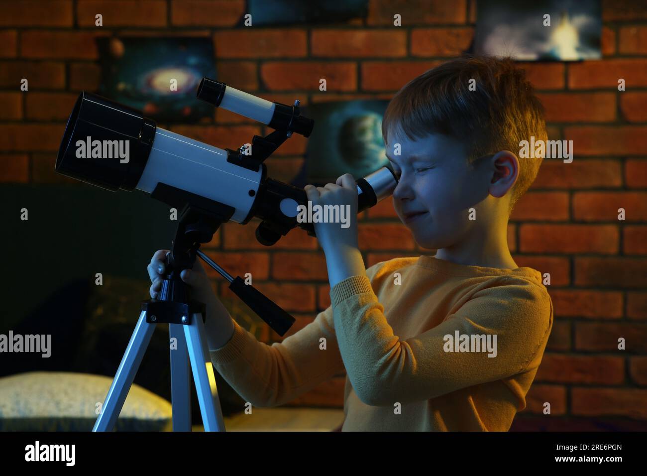 Little boy looking at stars through telescope in room Stock Photo - Alamy