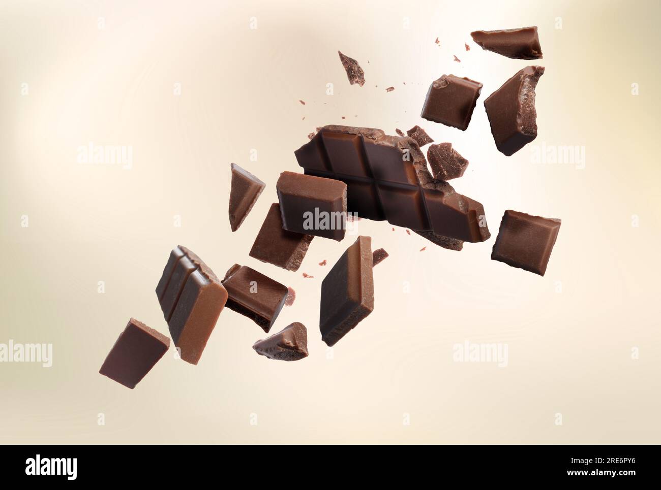 Broken chocolate bar pieces falling on beige background Stock Photo - Alamy