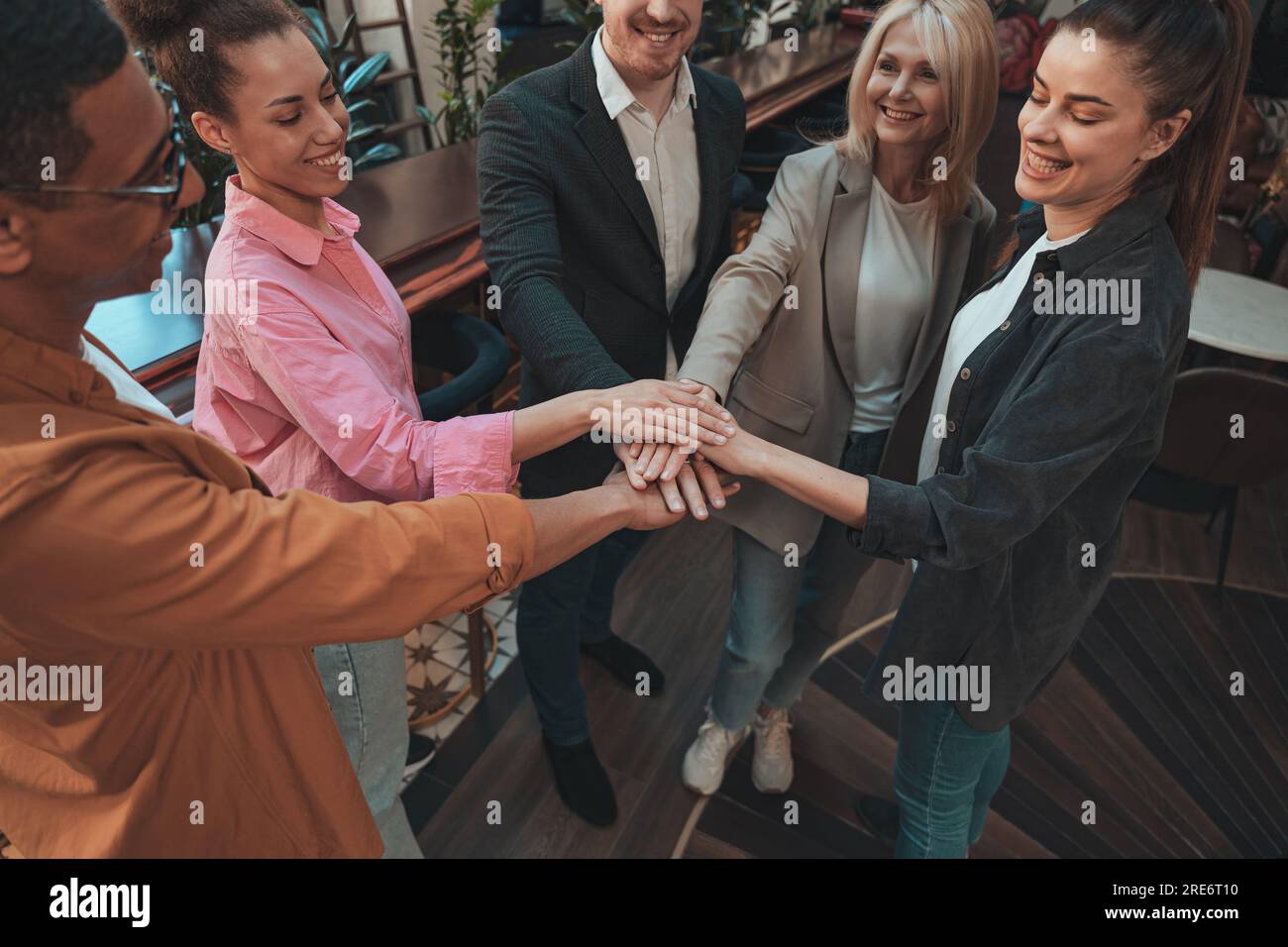 Group of coworkers stacking hands together one by one in unity. Support ...