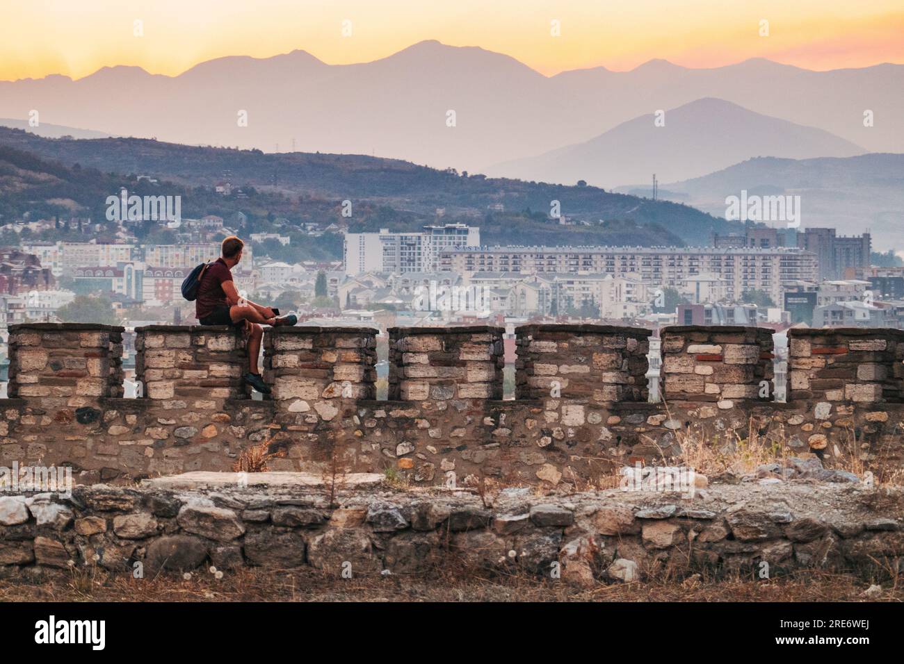 A tourist sits on a stone wall at Kale Fortress, Skopje, North ...