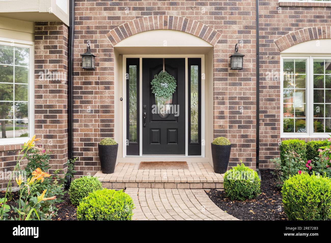The front door of a brick home with a black front door and a stone path ...