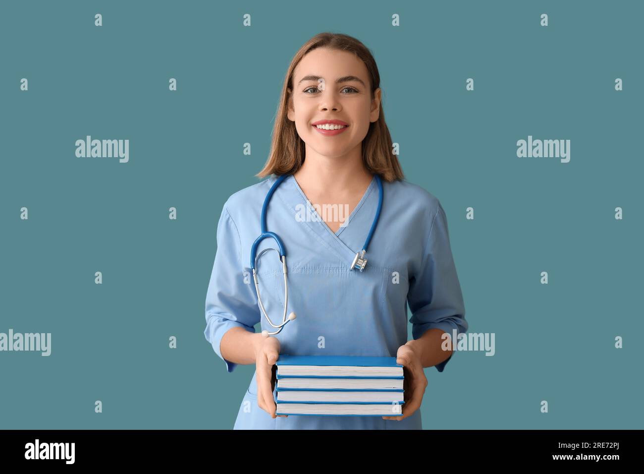Female intern with books on blue background Stock Photo - Alamy