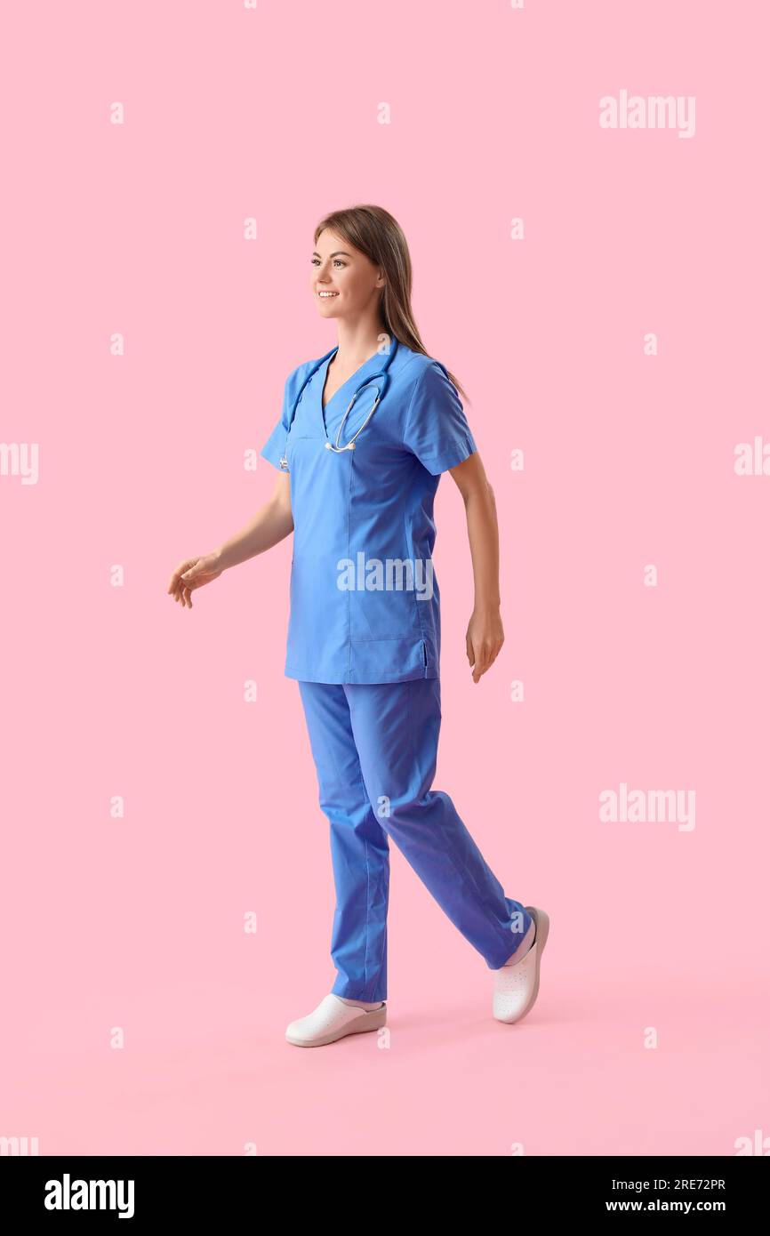 Female medical intern walking on pink background Stock Photo - Alamy