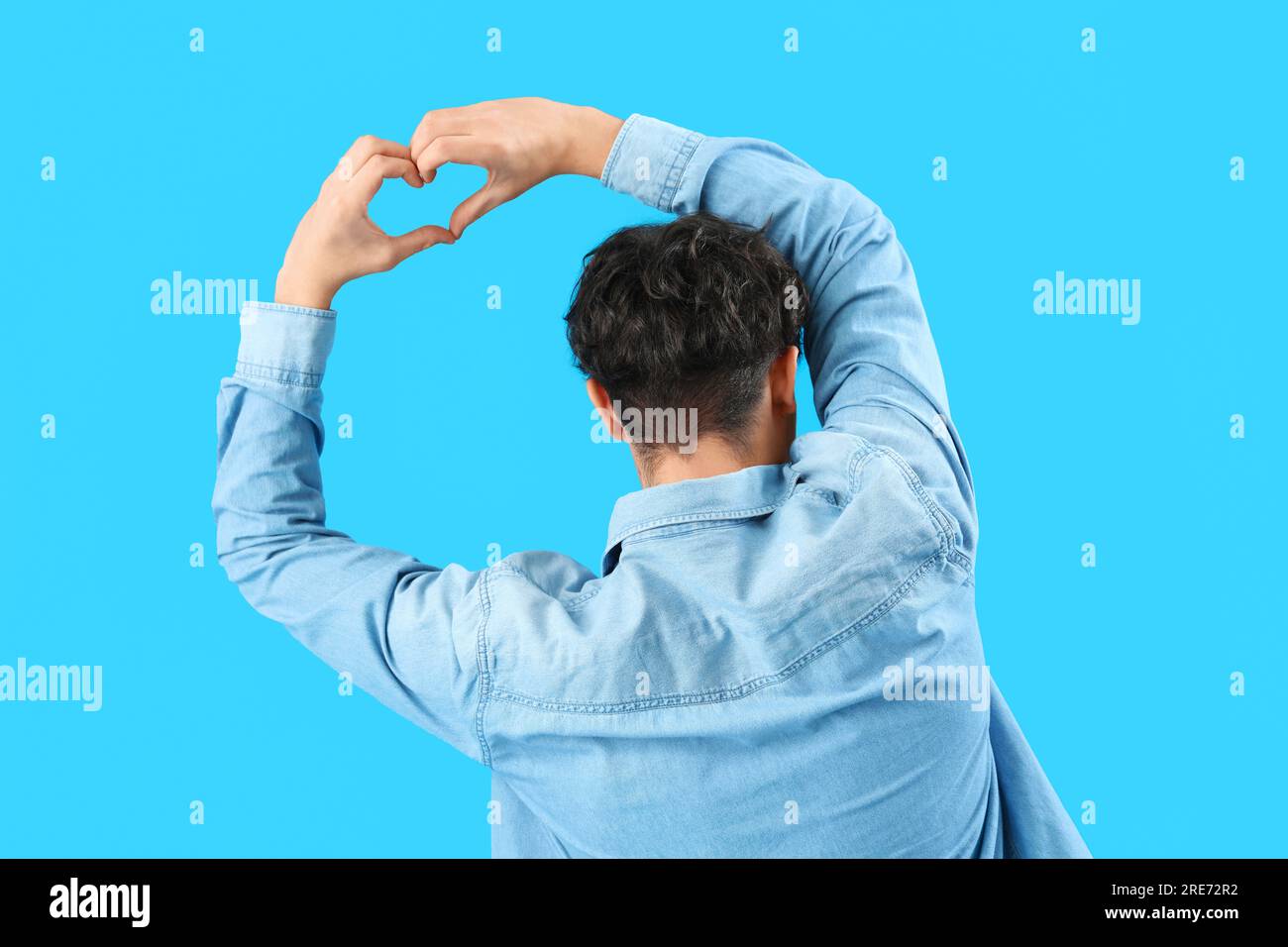Handsome young man making heart with his hands on light blue background ...