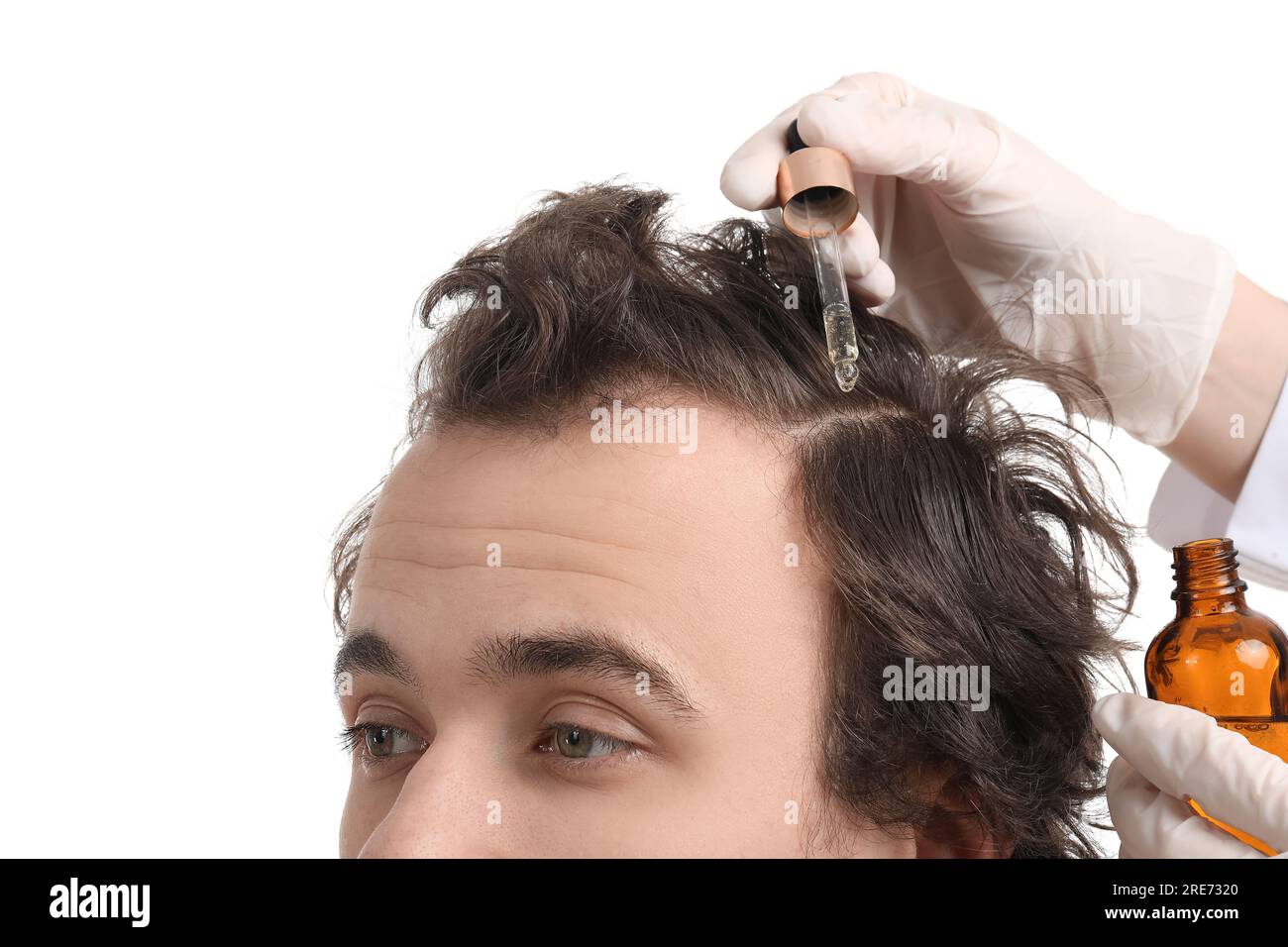 Young man receiving serum for hair growth on white background, closeup ...