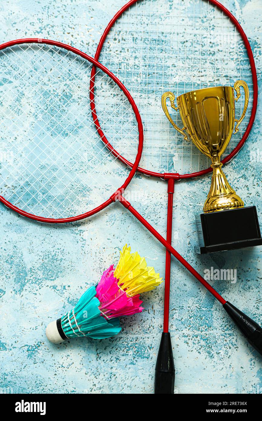 Gold cup with badminton rackets and shuttlecocks on grunge background ...