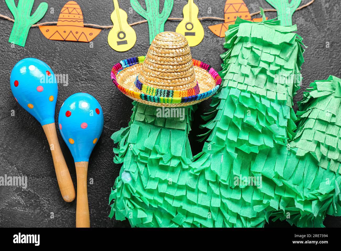 Mexican maracas with sombrero hat, pinata and garland on dark ...