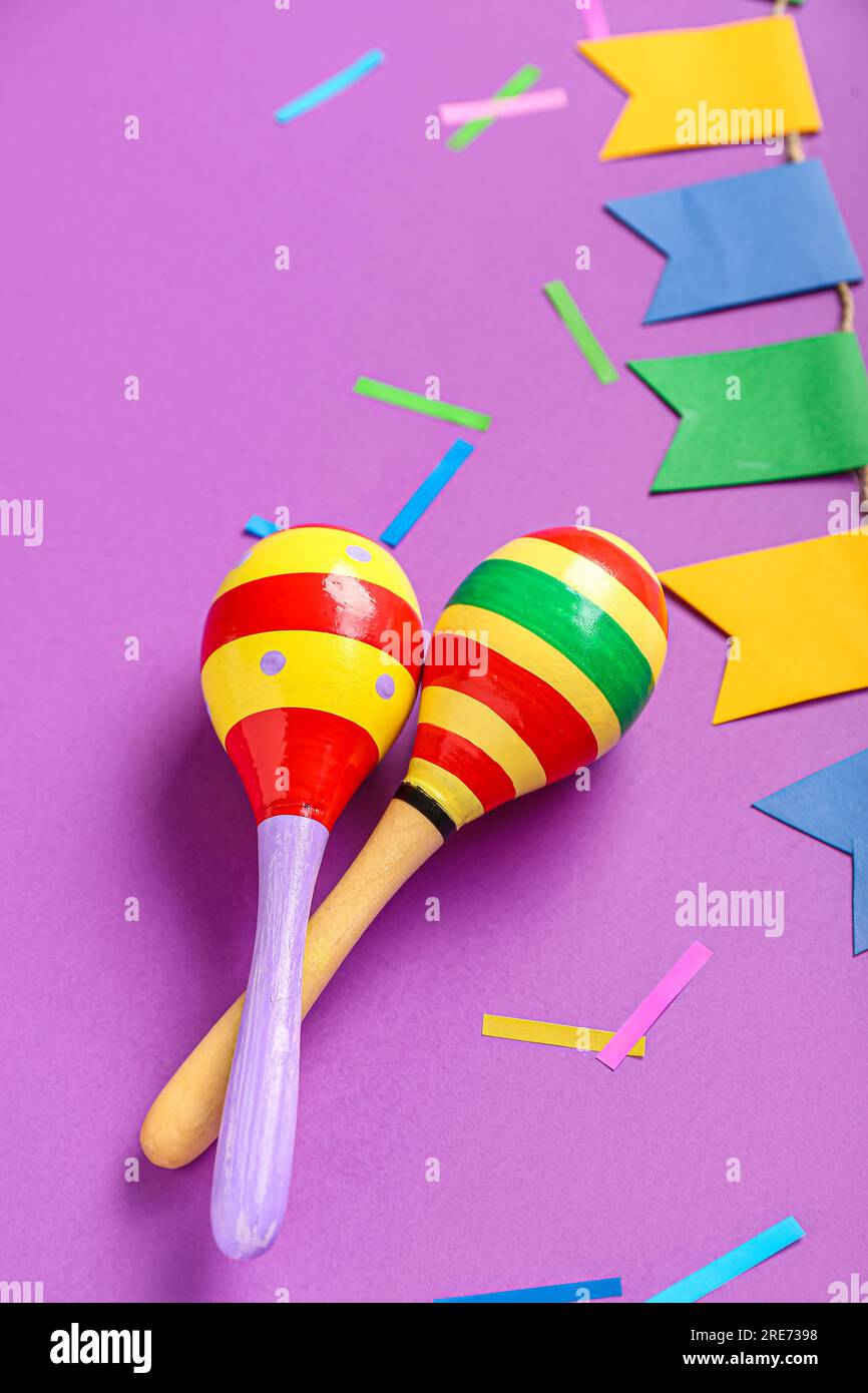 Mexican maracas with paper flags and confetti on purple background ...