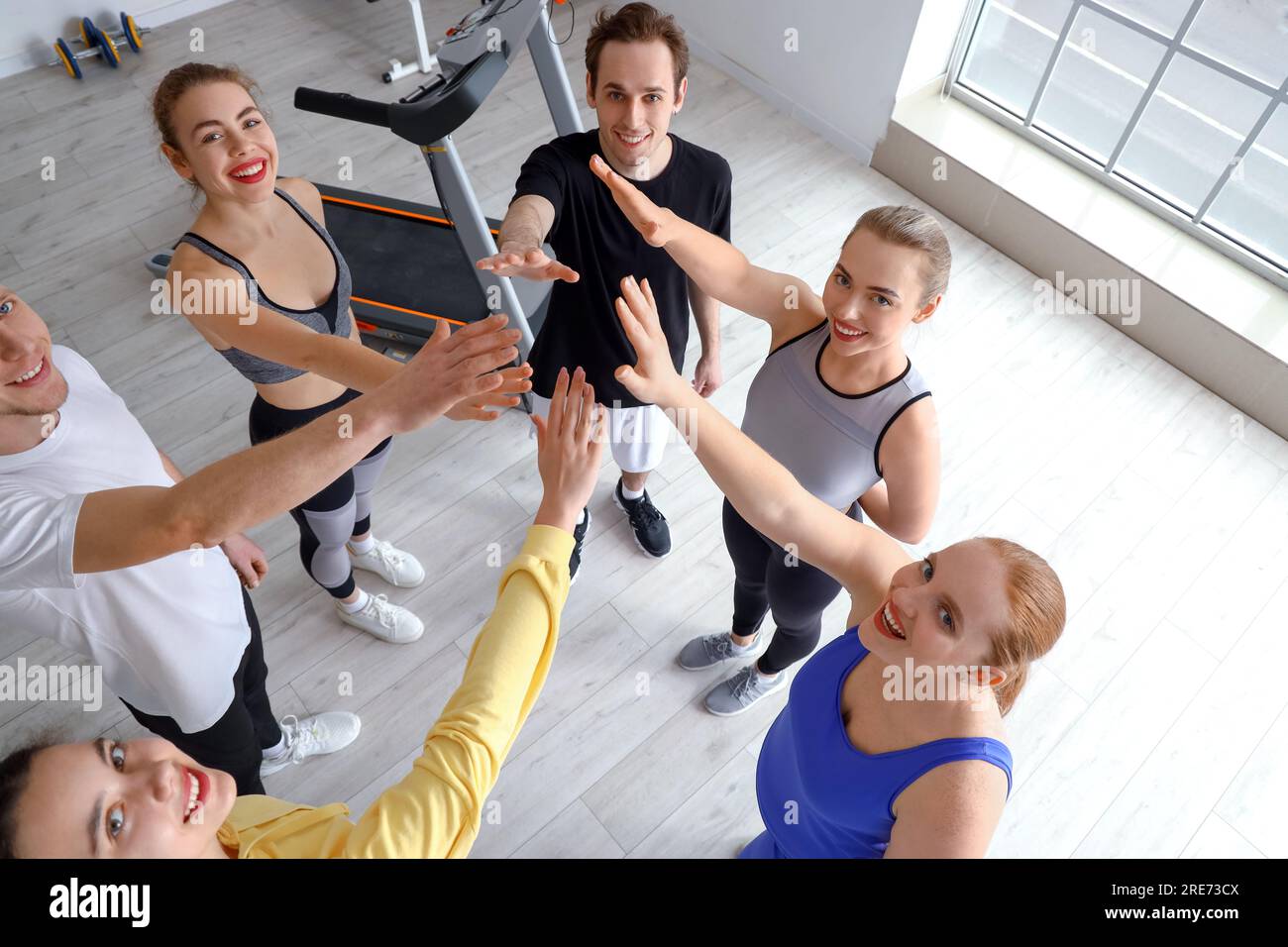 Group of sporty young people putting hands together in gym Stock Photo ...