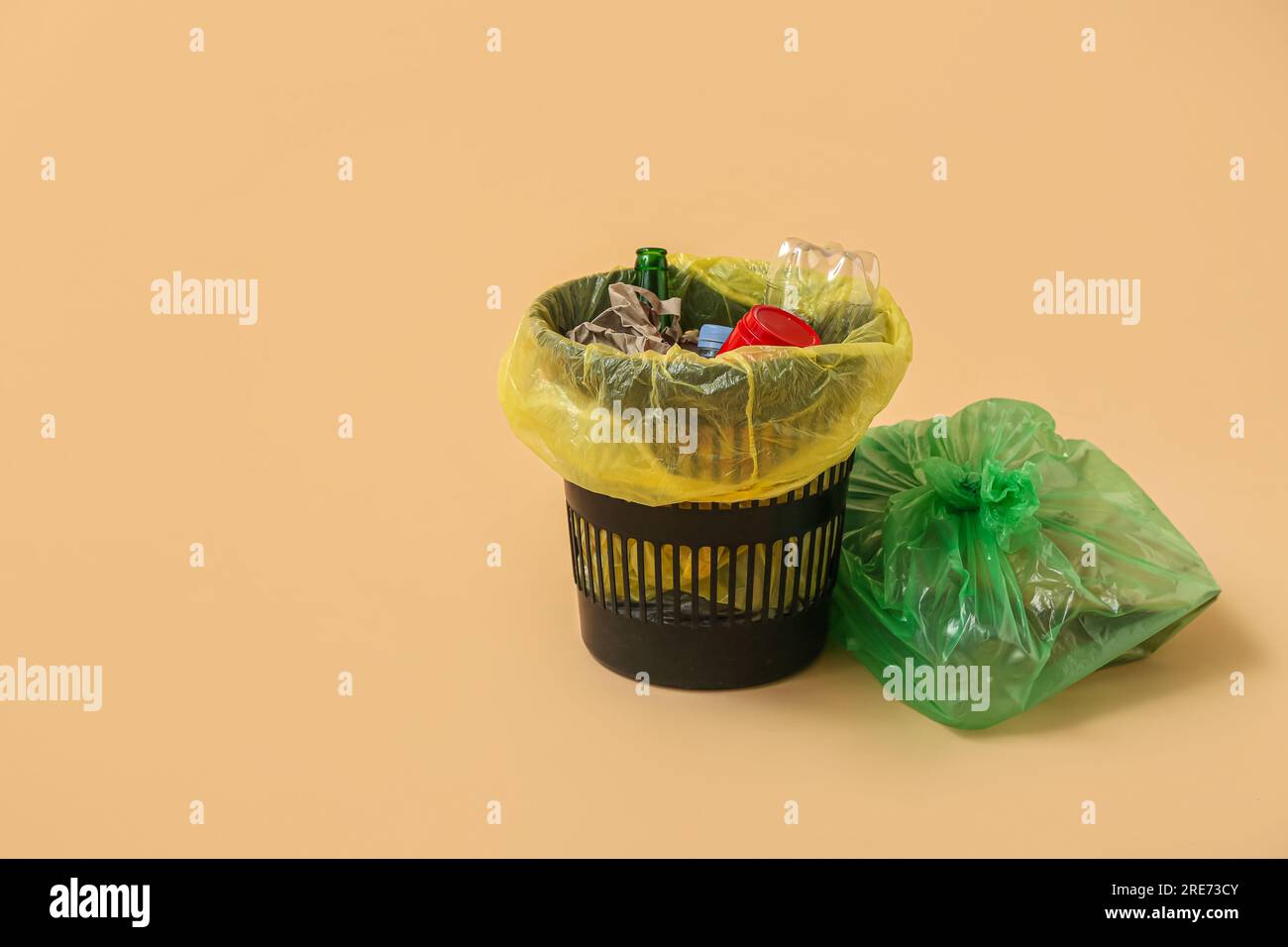 Full trash bin and garbage bag on beige background Stock Photo - Alamy
