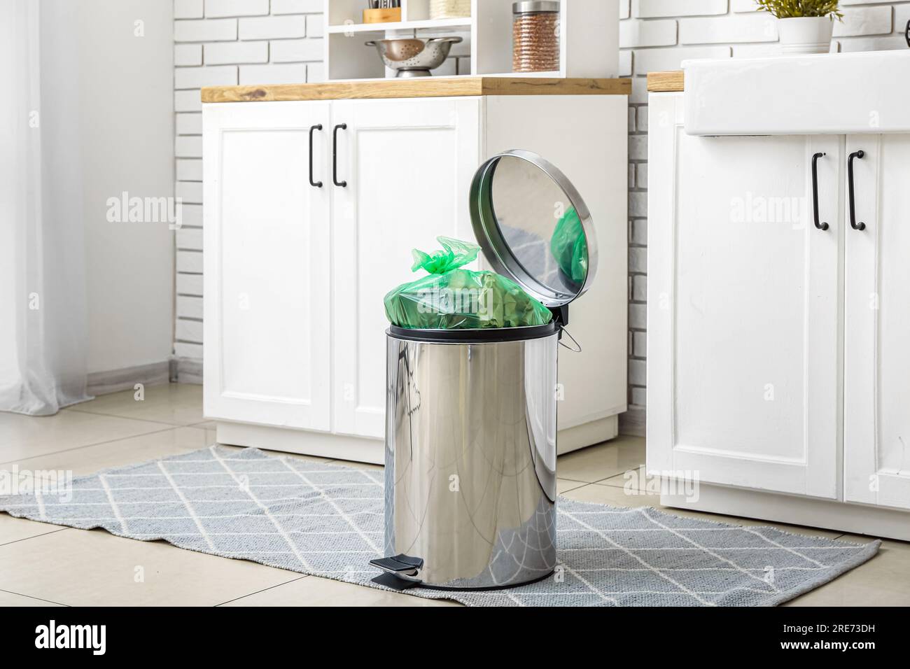 Full trash bin in interior of modern kitchen Stock Photo - Alamy