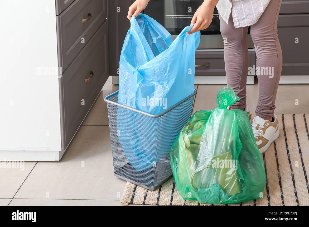 Woman placing garbage bag into empty trash bin in kitchen Stock Photo ...