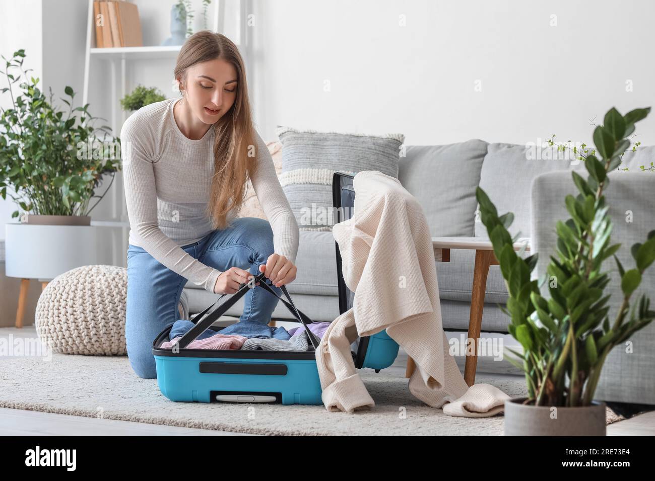 Young woman unpacking suitcase at home Stock Photo - Alamy