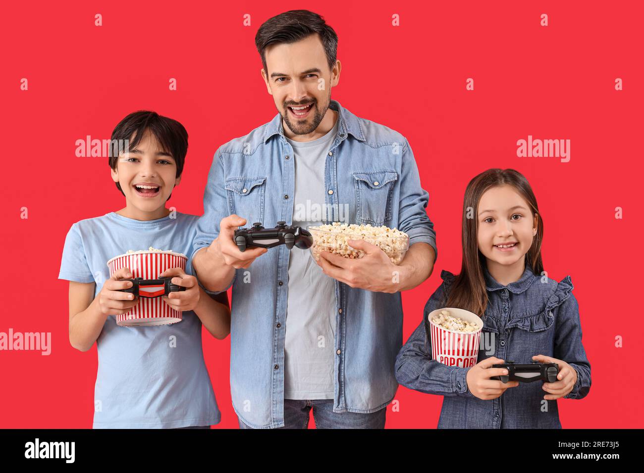 Little children with their father and popcorn playing video game on red ...