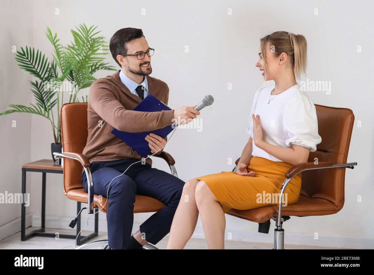 Male journalist with microphone having an interview with woman in ...