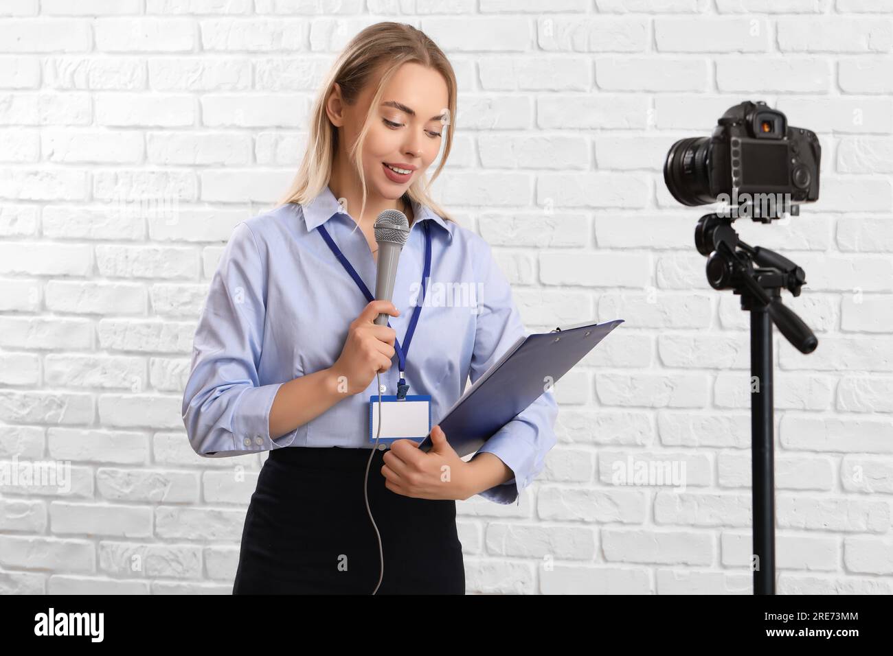 Female journalist with microphone and clipboard recording video on ...